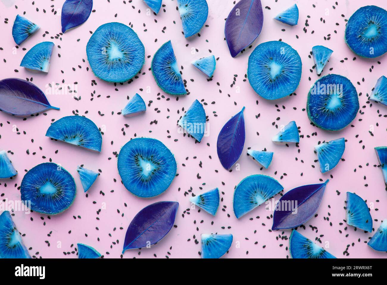 Lay flat sliced blue kiwi with seeds on solid pink background, summer ...