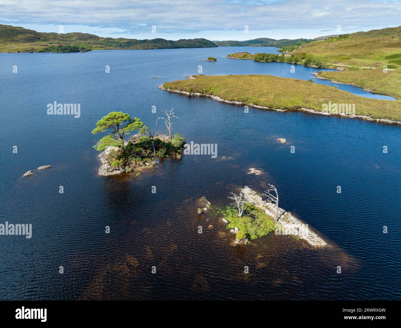 Aerial view of the freshwater loch Loch Assynt with small tree islands ...