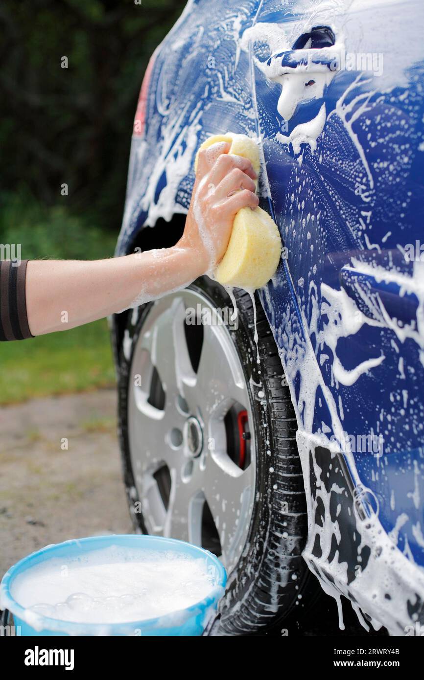 A Hand washing a blue car with a sponge Stock Photo - Alamy