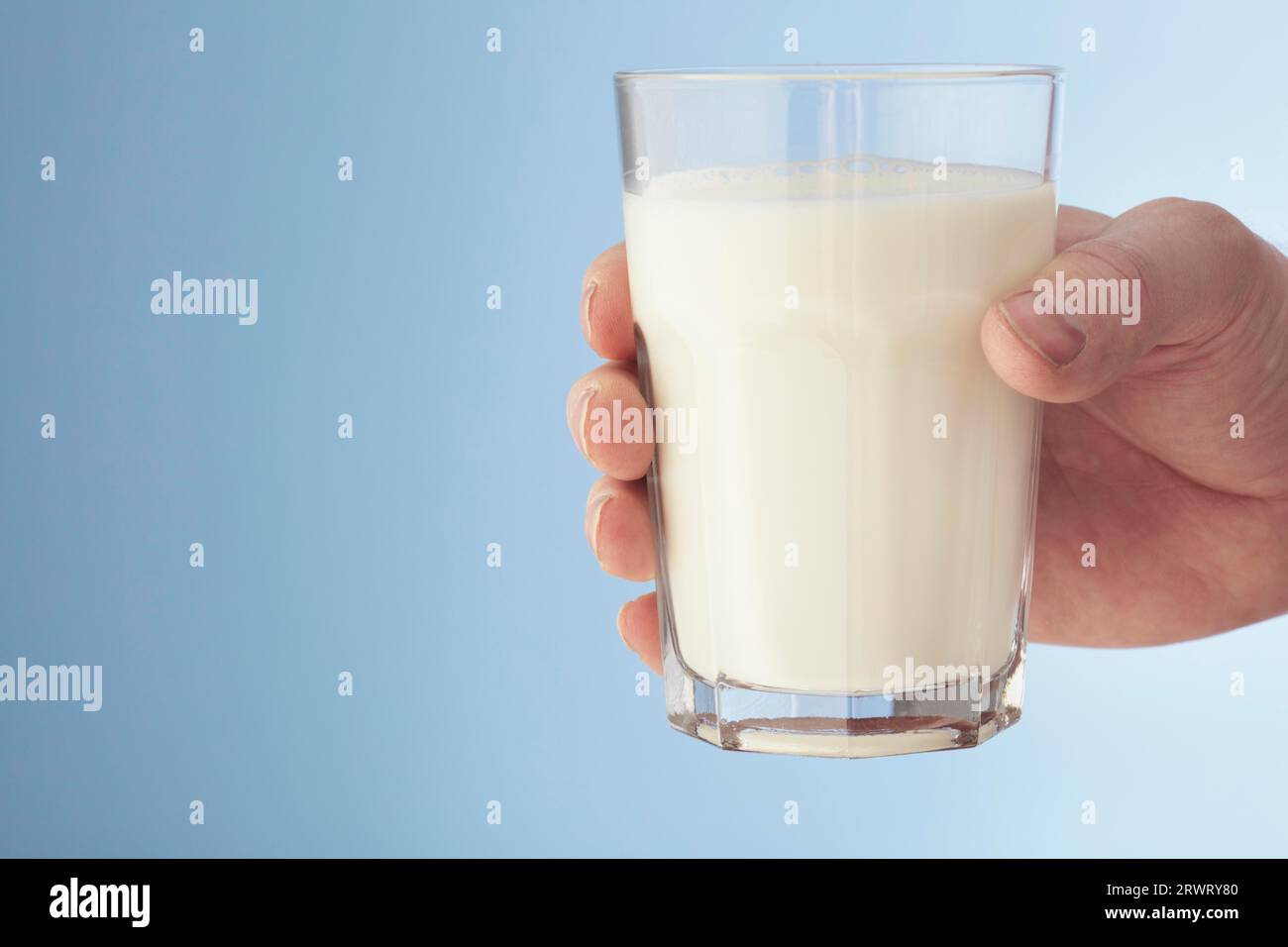A Hand holding a glass of milk. Copy space on the left Stock Photo - Alamy