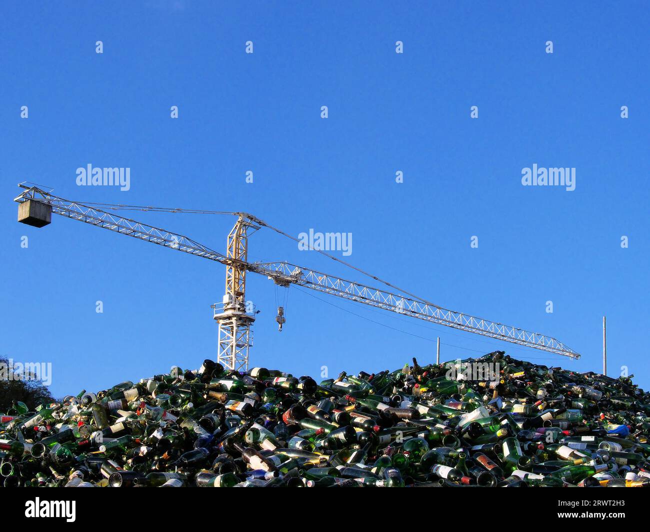 Crane in front of a huge pile of waste glass, mainly green glass Stock ...