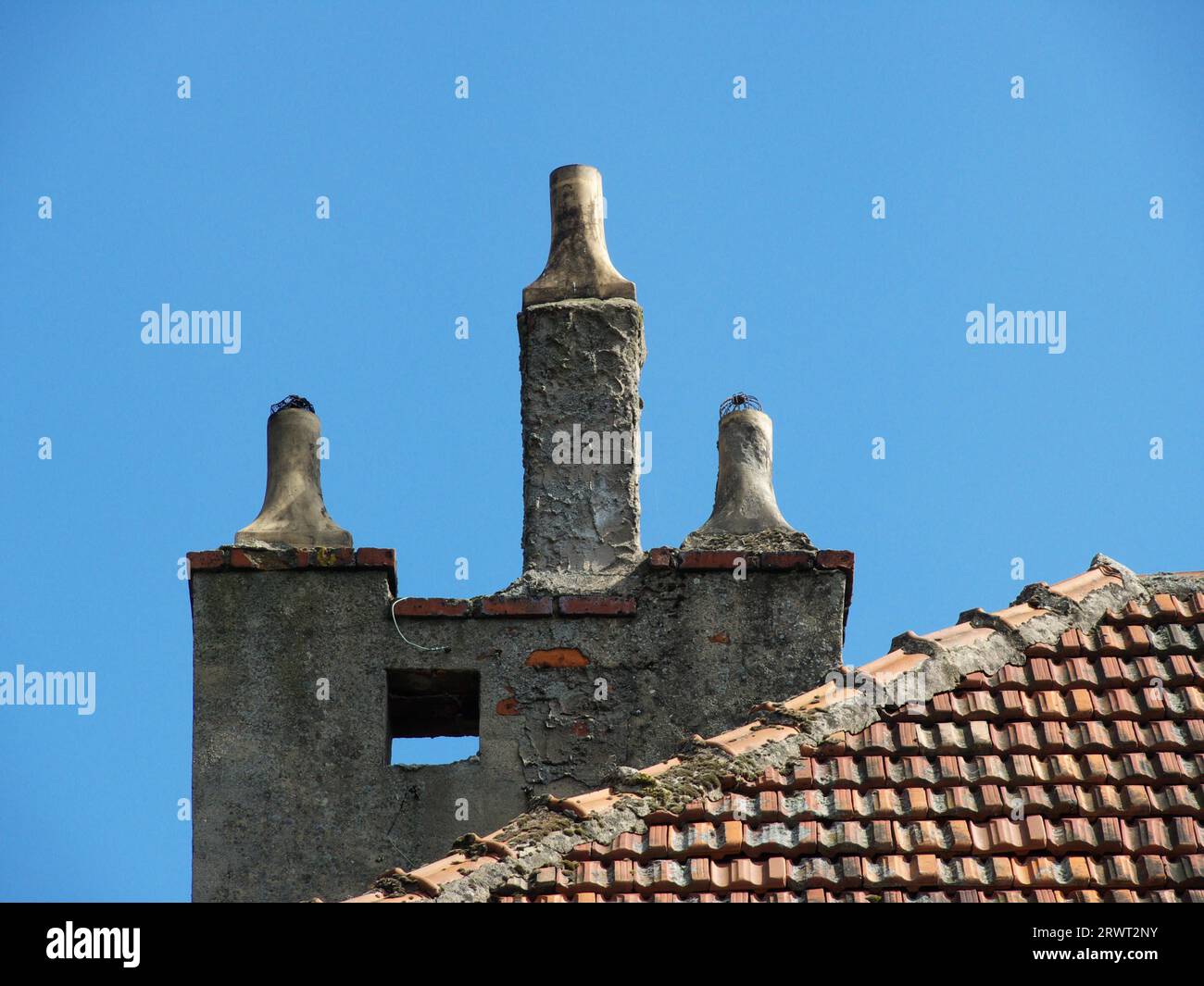 Three chimneys with a section of the roof, blue sky in the background ...