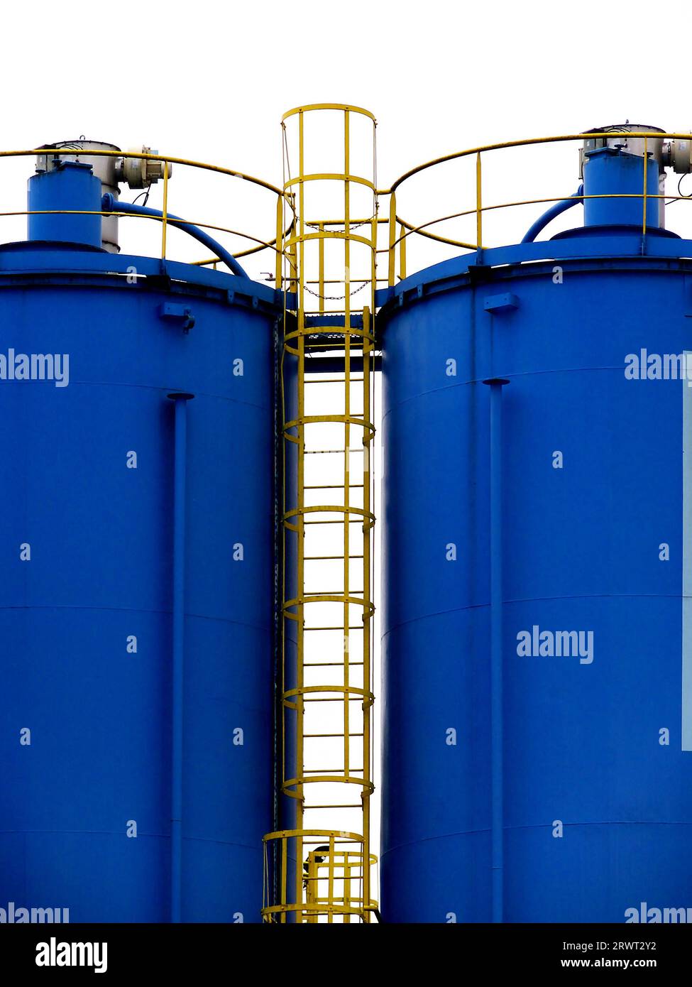 Two dark blue silos, in the middle a yellow stairway Stock Photo - Alamy