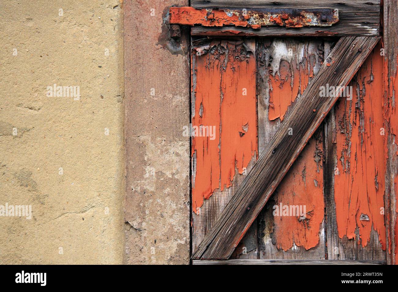 Formerly orange-painted wooden shutter on house wall, detail Stock ...