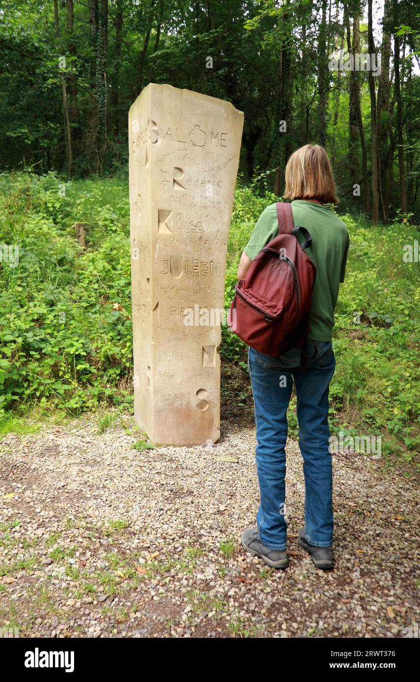 Male person, early 50s, hiker, looking at boundary stone with carvings ...