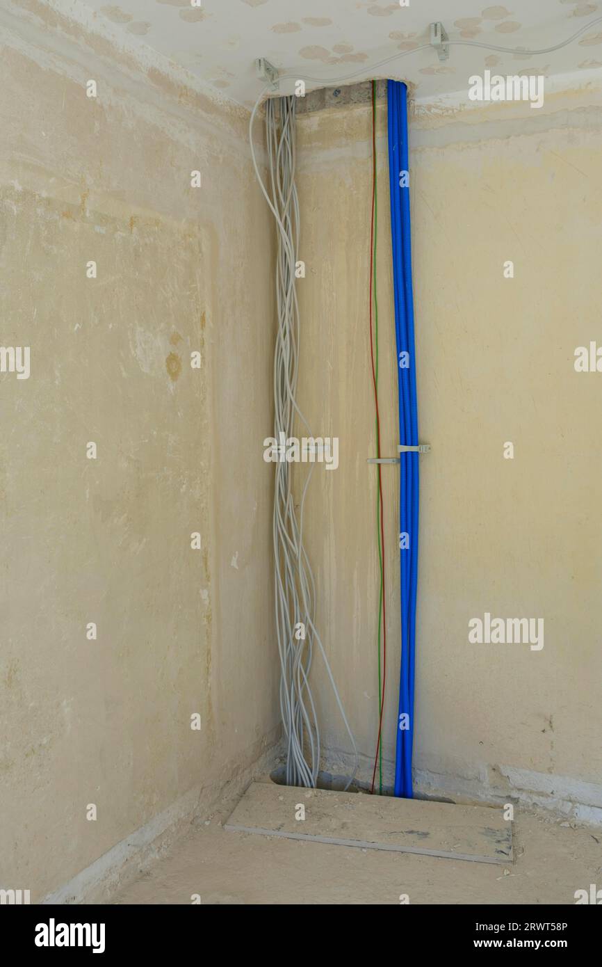 Electric cables and empty conduits on a wall, construction site ...