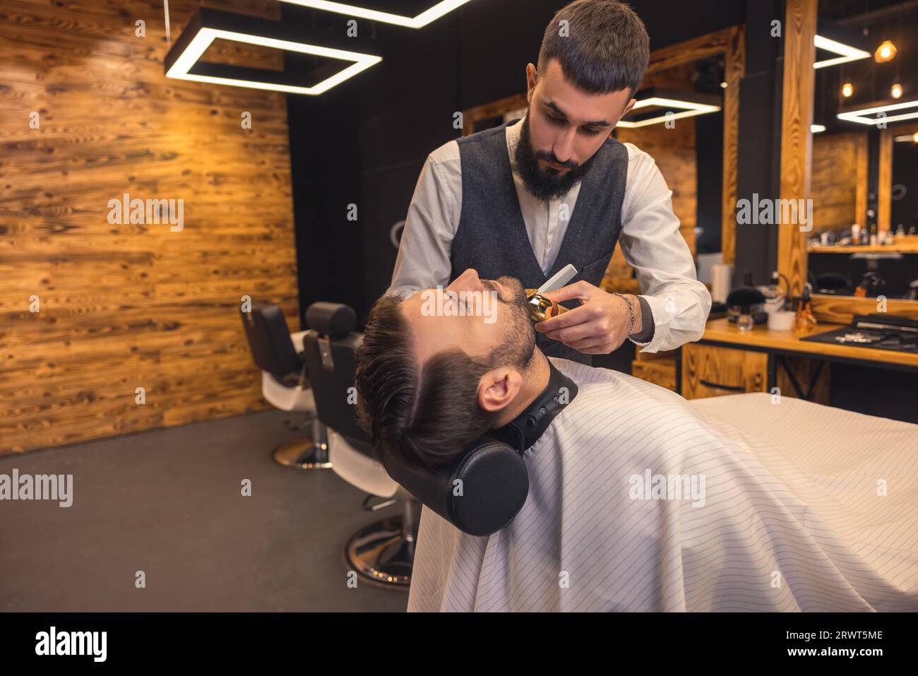 Bearded man getting beard haircut by hairdresser at barbershop Stock ...