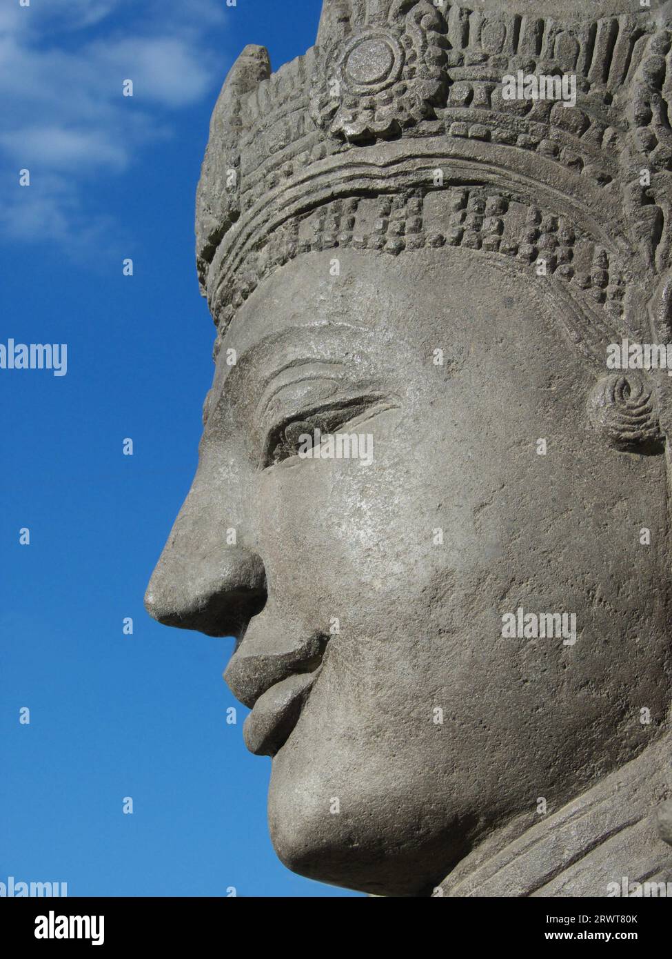 Half-portrait of an Indian sculpture, background bright blue sky with a ...