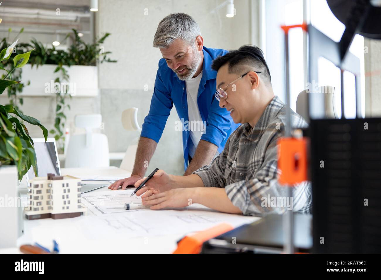 Men working with 3D printer and blueprint for designing mechanical ...
