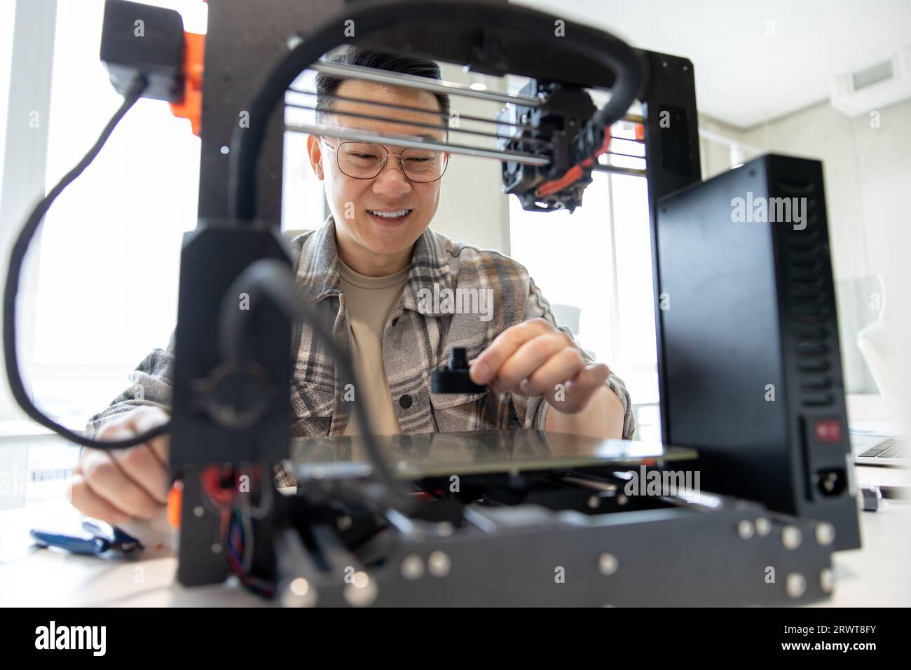 Engineering man designing mechanical parts using 3D printer in office ...