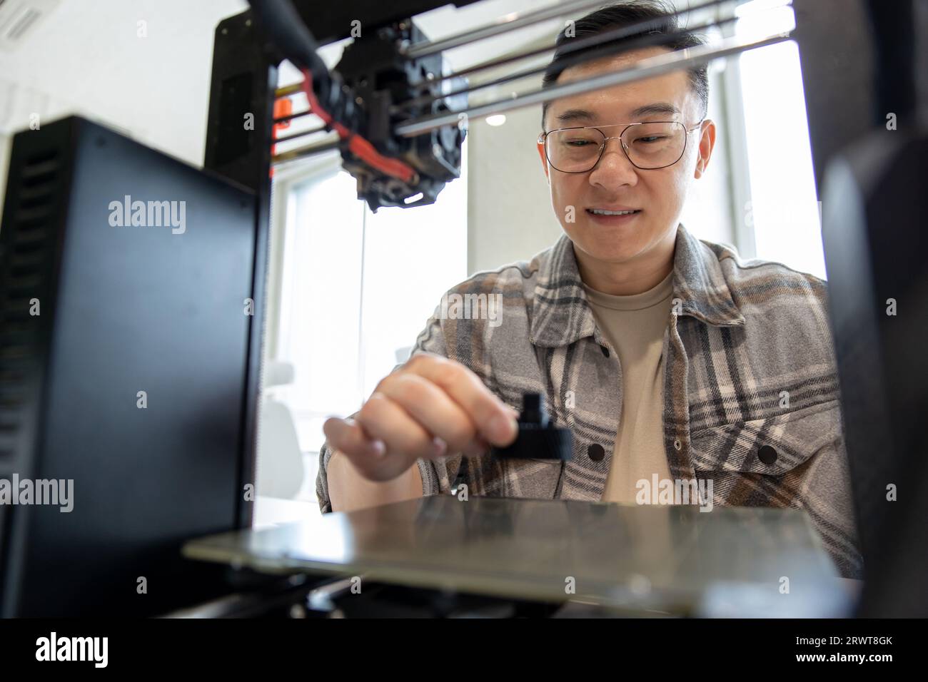 Engineering man designing mechanical parts using 3D printer in office ...
