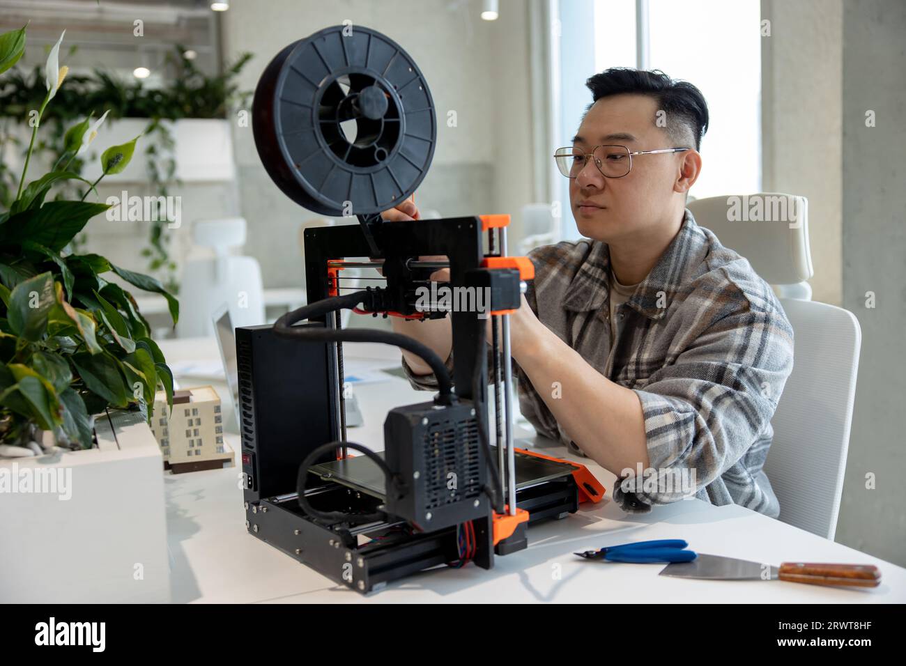 Engineering man designing mechanical parts using 3D printer in office ...