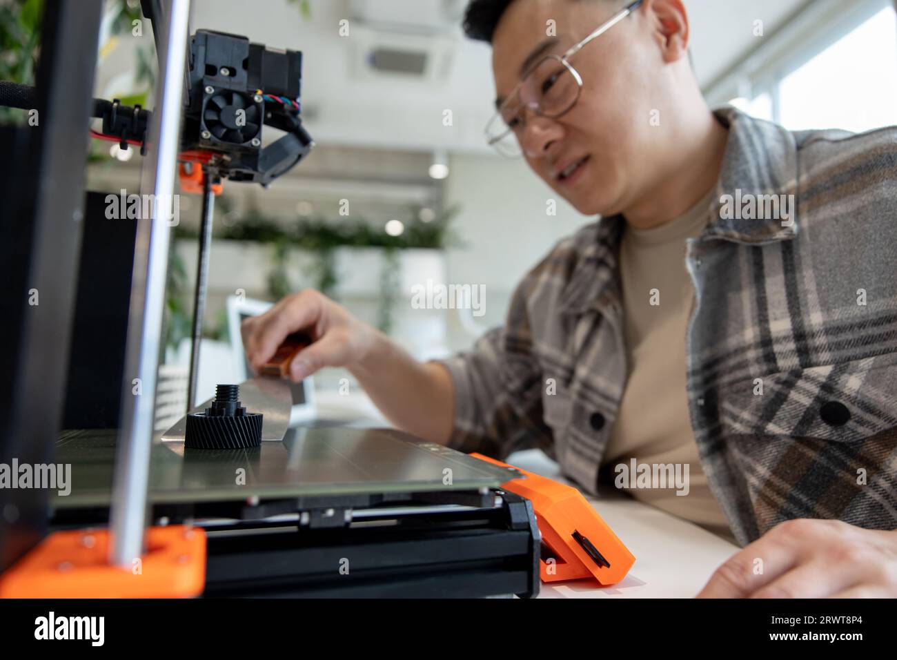 Asian designer engineer using 3D printer in laboratory and studying ...
