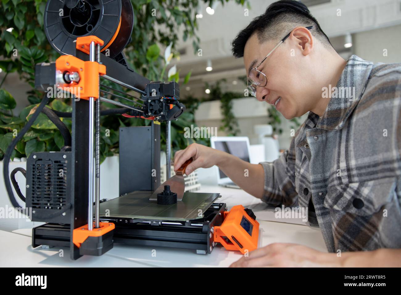 Asian designer engineer using 3D printer in laboratory and studying ...