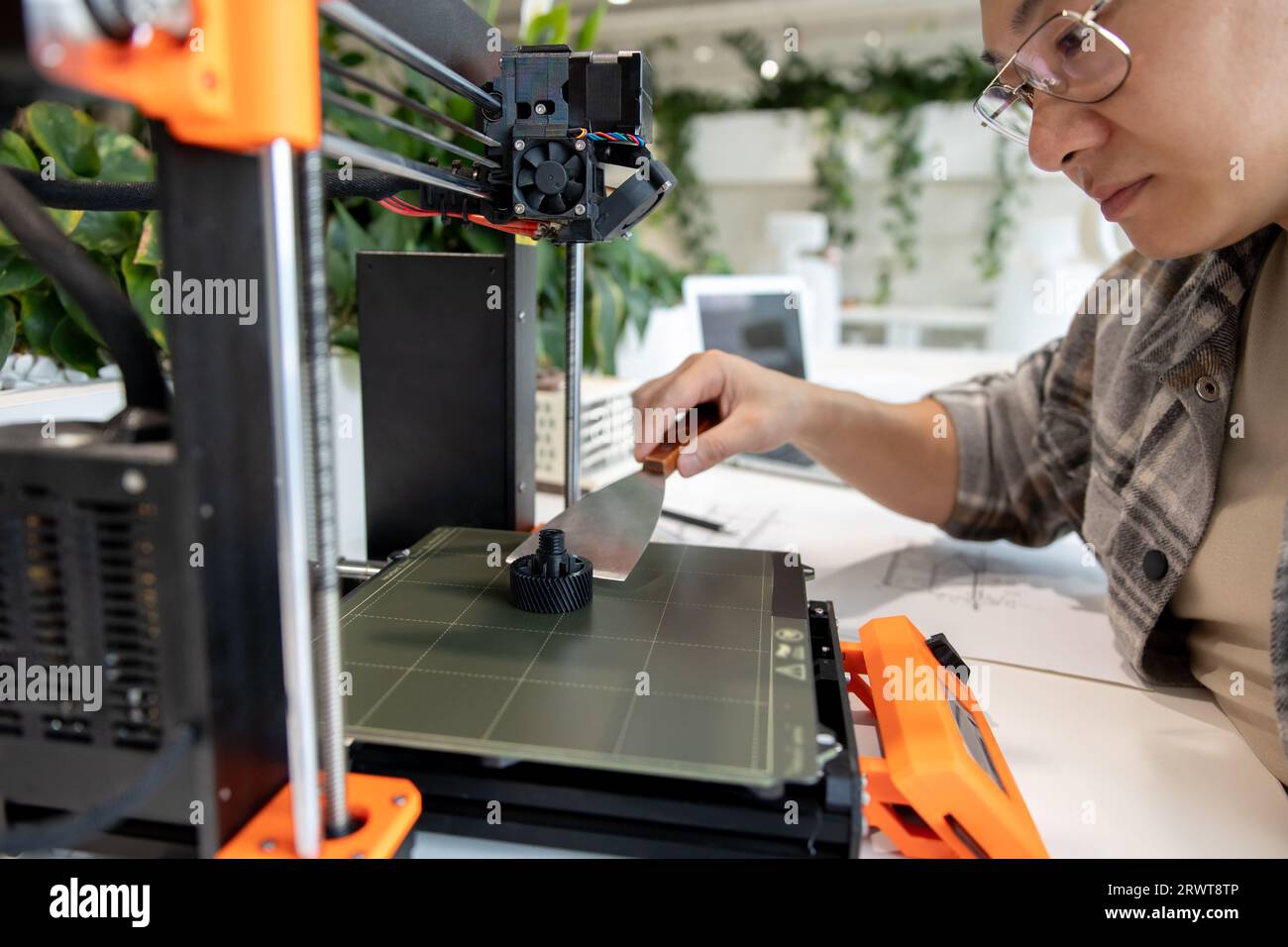 Asian designer engineer using 3D printer in laboratory and studying ...