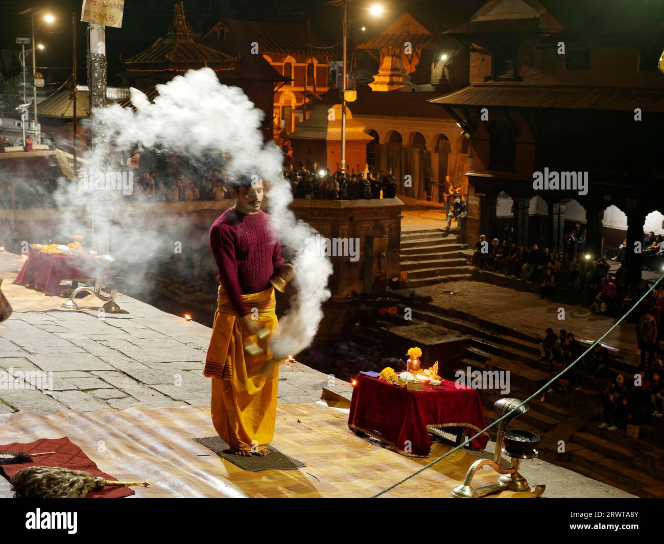 Hindu priest performing a ritual with smoke at night in front of the ...