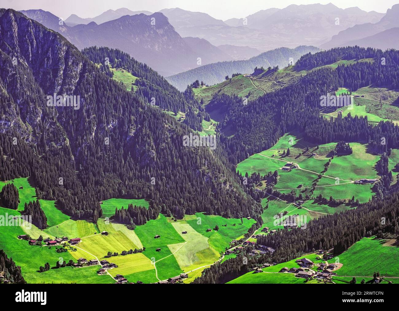 Birds-eye view of farm land, houses, trees & mountains in the ...