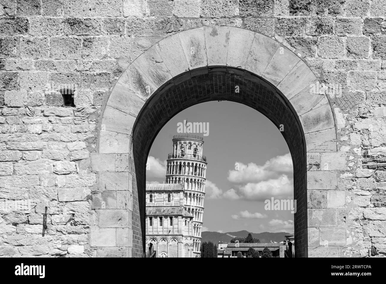 View of the Leaning Tower of Pisa from the city gate in black and white ...