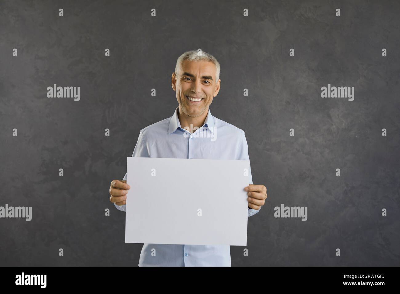 Portrait of smiling senior man presenting white blank sheet of paper ...