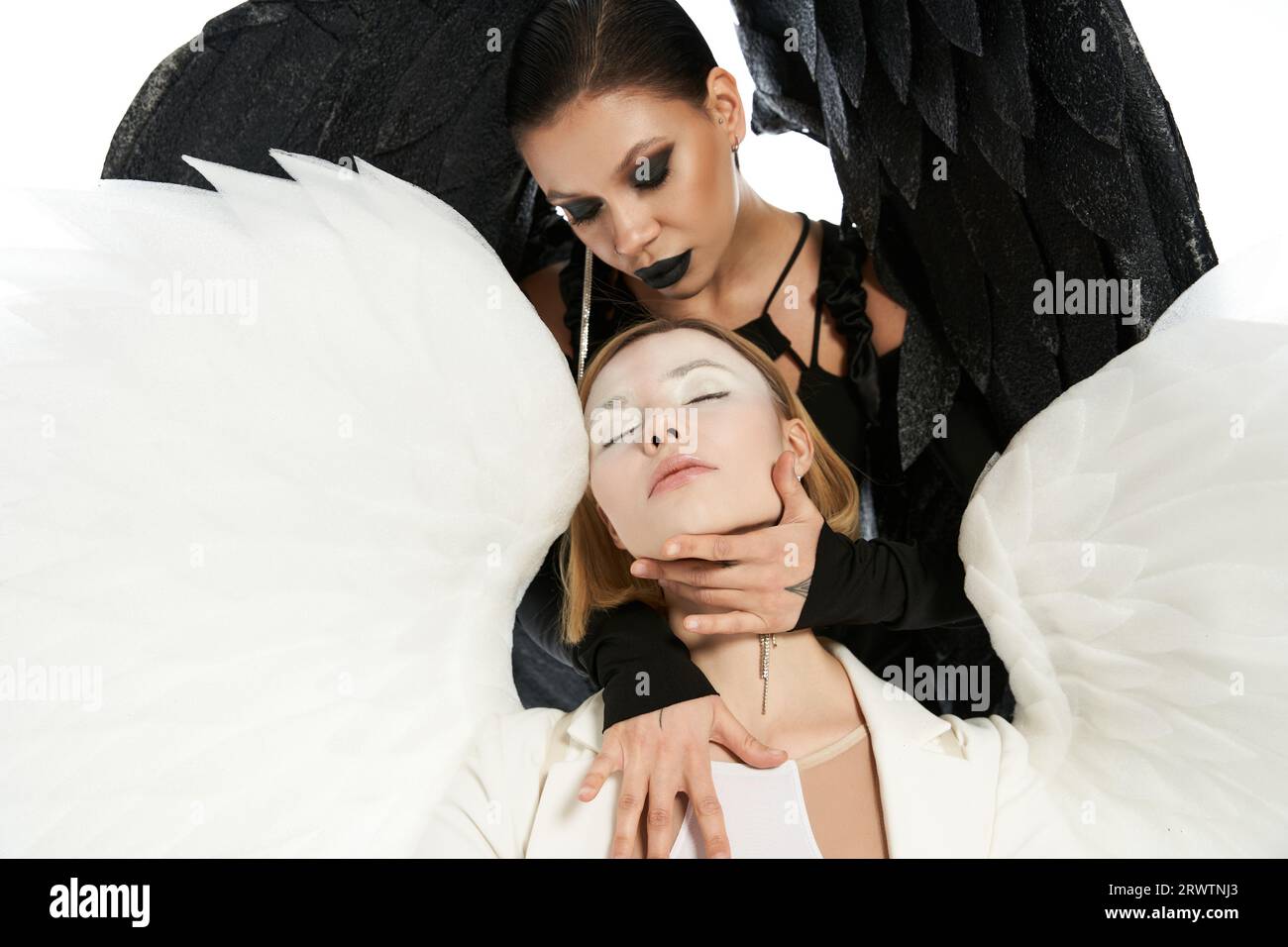 sinister demon tempting ethereal angel with closed eyes on white, good ...