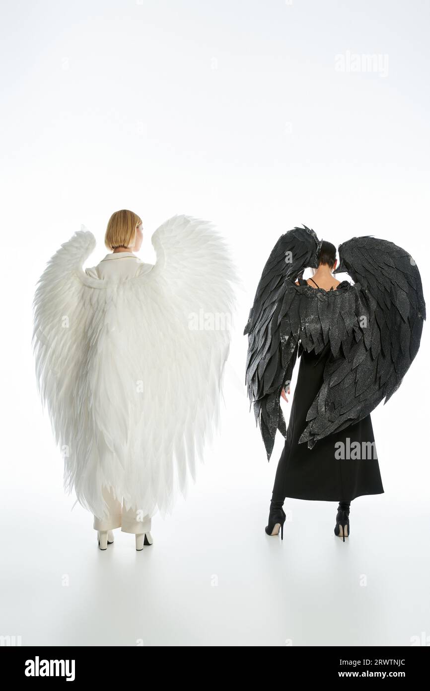 back view of women in costumes of devil and angel with black and light ...