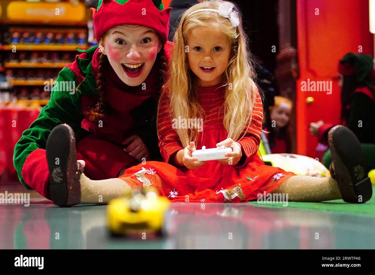 A young girl and an elf play with the Hamleys, Magic Moving Car at the ...