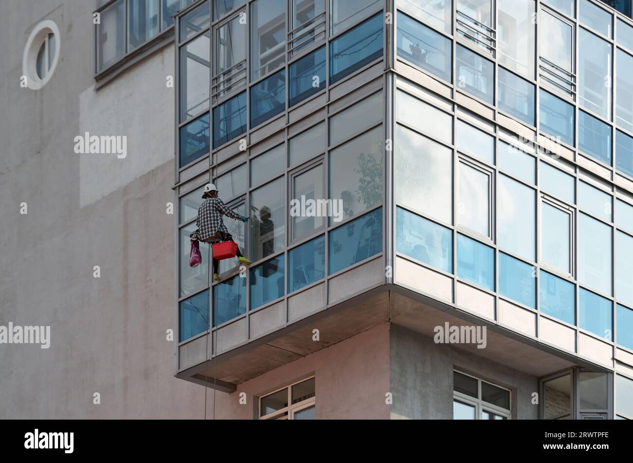 A window cleaner washes the glazing of a high-rise building's balcony ...