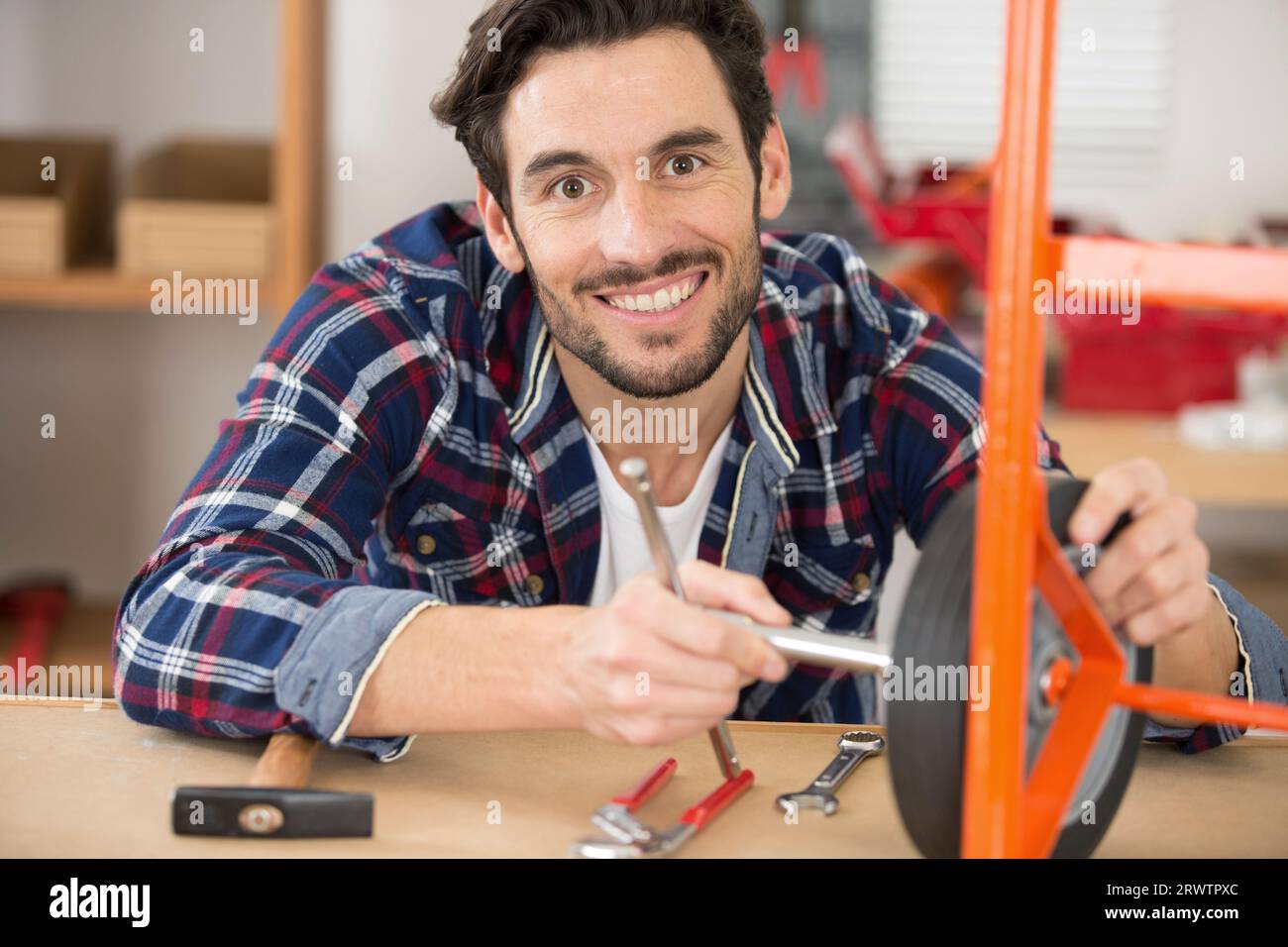 happy man smiling at the camera while fixing wheels trolley Stock Photo ...