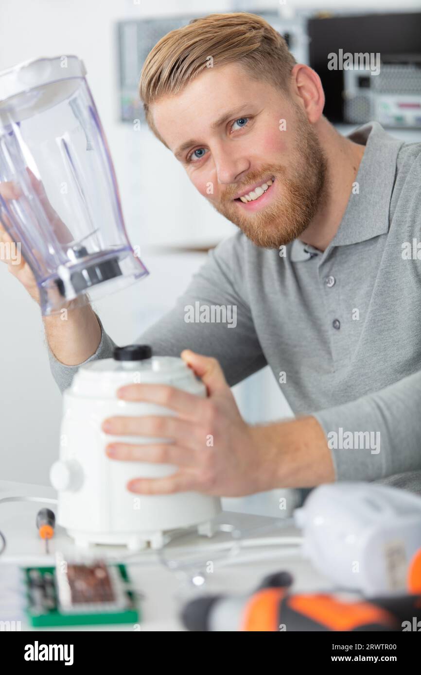 man sitting by desk repairing blender Stock Photo - Alamy