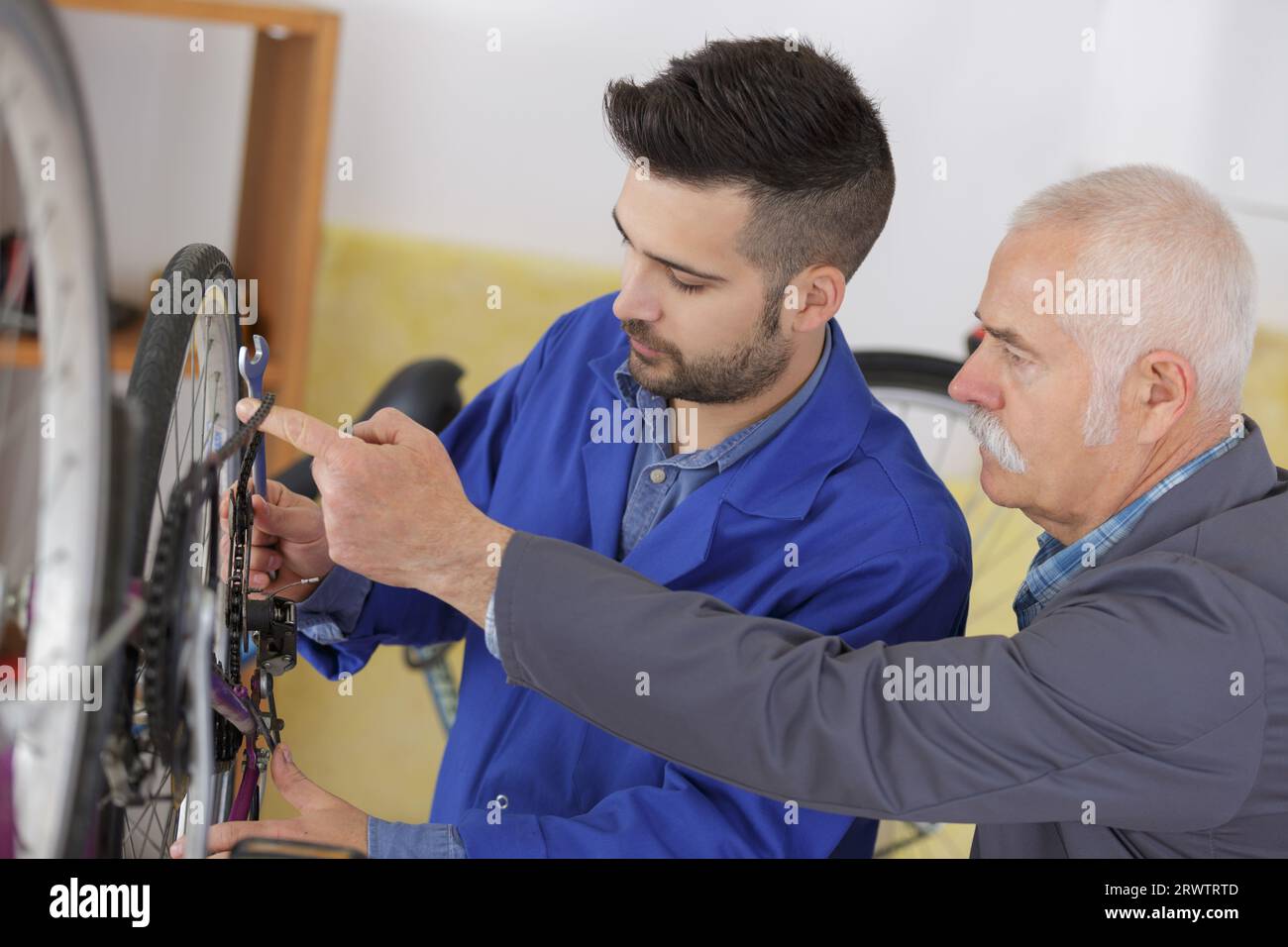 bicycle mechanic and apprentice repairing a bike in workshop Stock ...