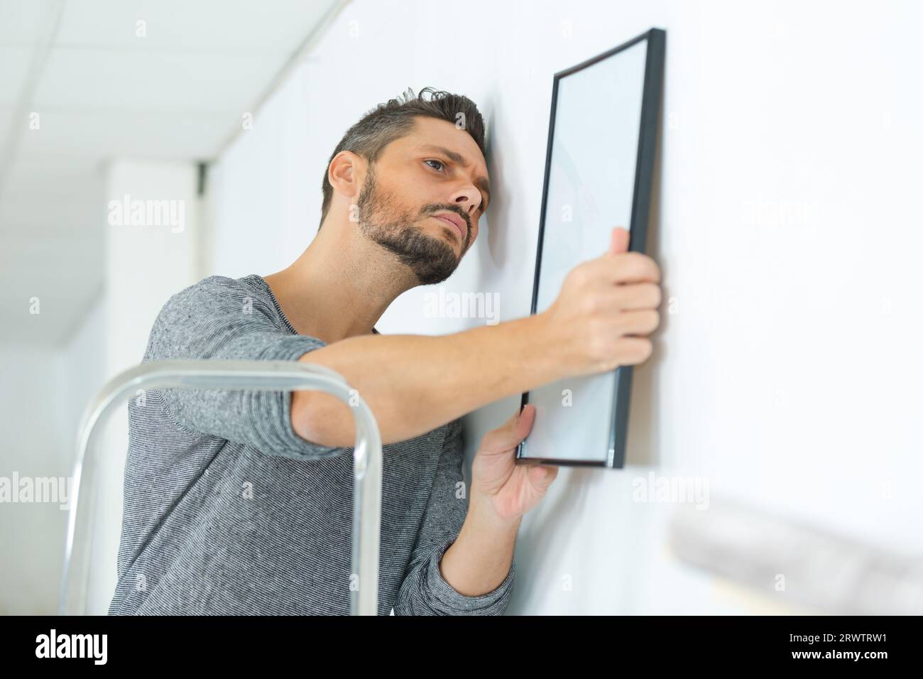 repairman putting picture frame onto wall Stock Photo - Alamy