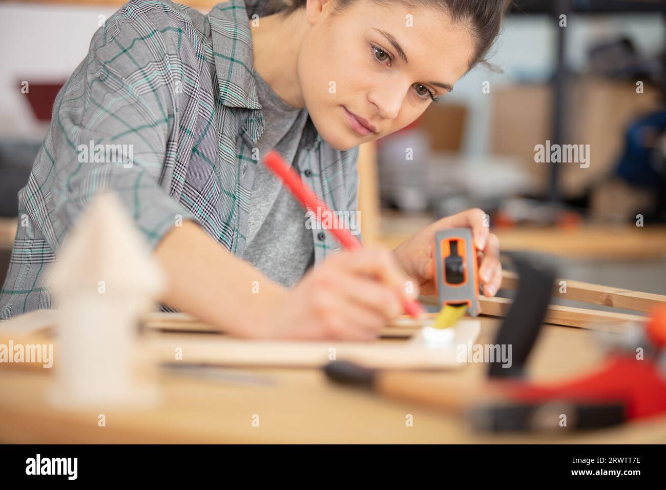 female carpenter measuring wood in a workshop Stock Photo - Alamy