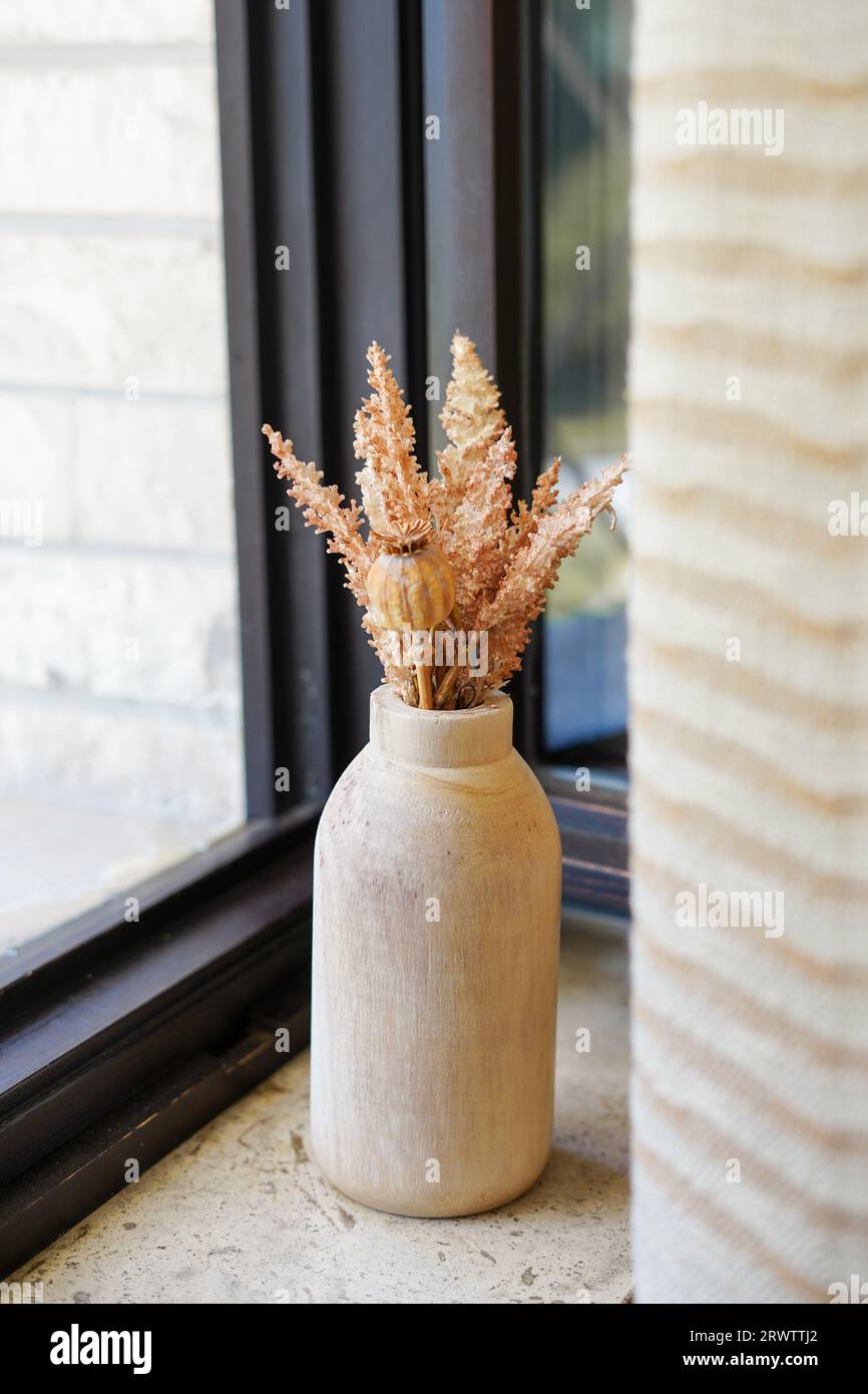 Dried flowers in wooden vase staying on the window sill. cozy home ...
