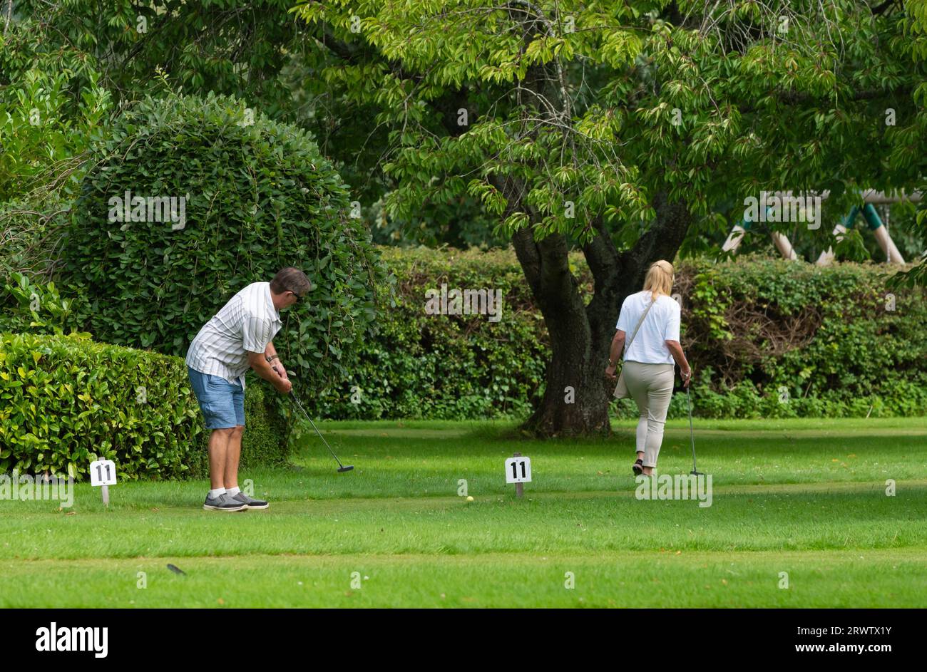 Middle aged man and woman, presumably a couple, playing putting or ...