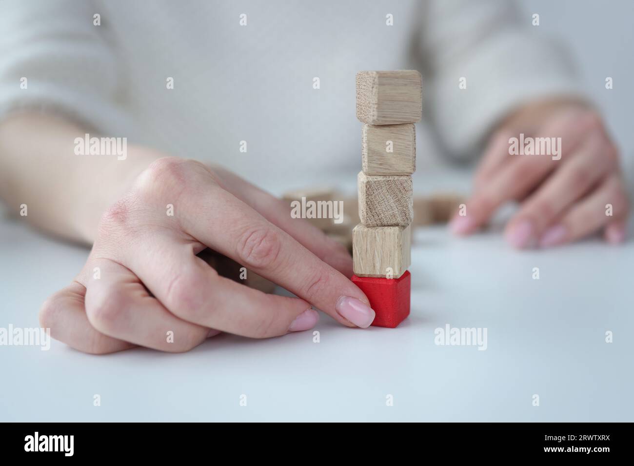 Female hand pulling out red wooden cube from base of tower closeup ...