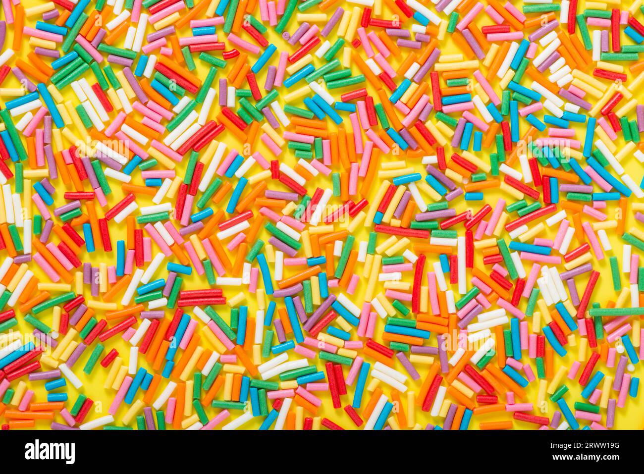 flat lay of colorful sprinkles over yellow background, festive ...