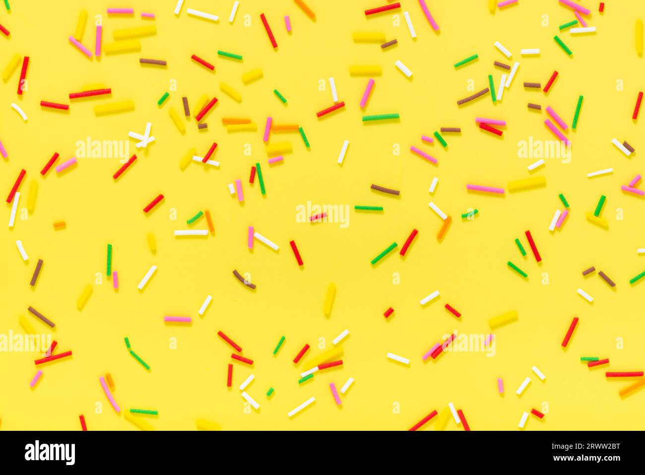 flat lay of colorful sprinkles over yellow background, festive ...