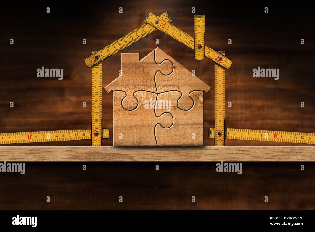 Wooden house made from a folding ruler and jigsaw puzzle pieces, on a ...