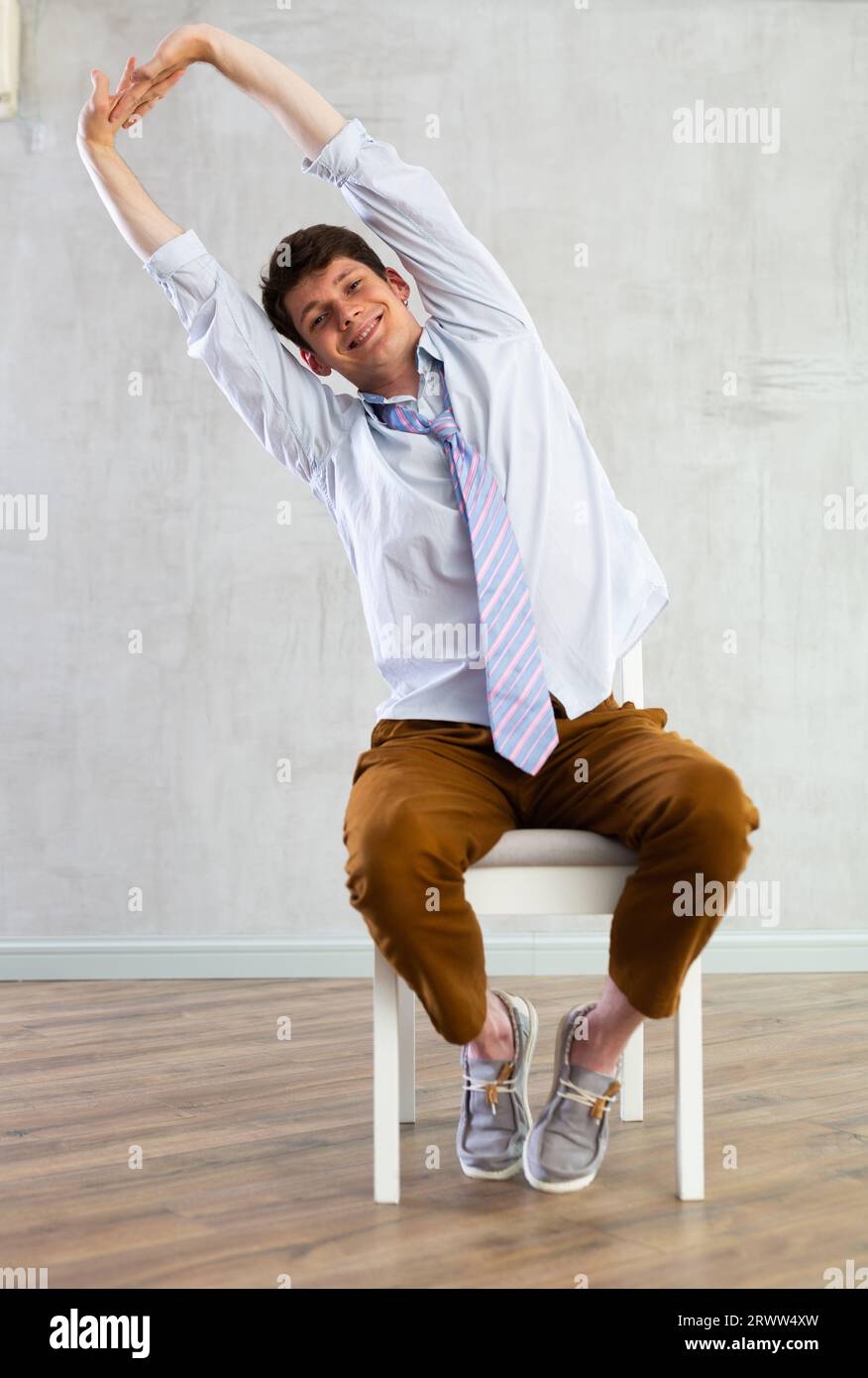 Young guy office worker doing exercises on chair Stock Photo - Alamy