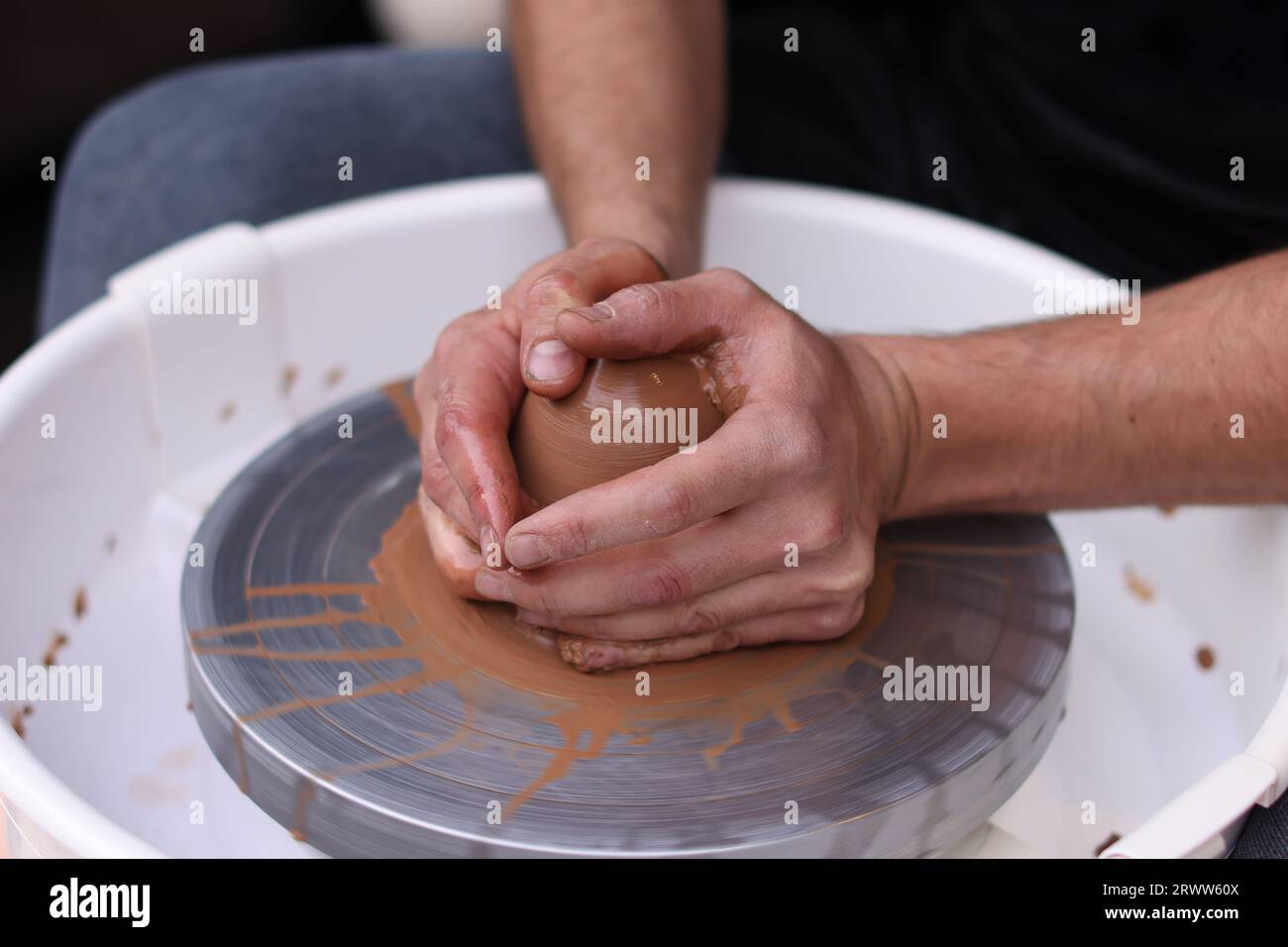 A male potter a ceramic vessel on a potter's wheel in a ceramics studio ...
