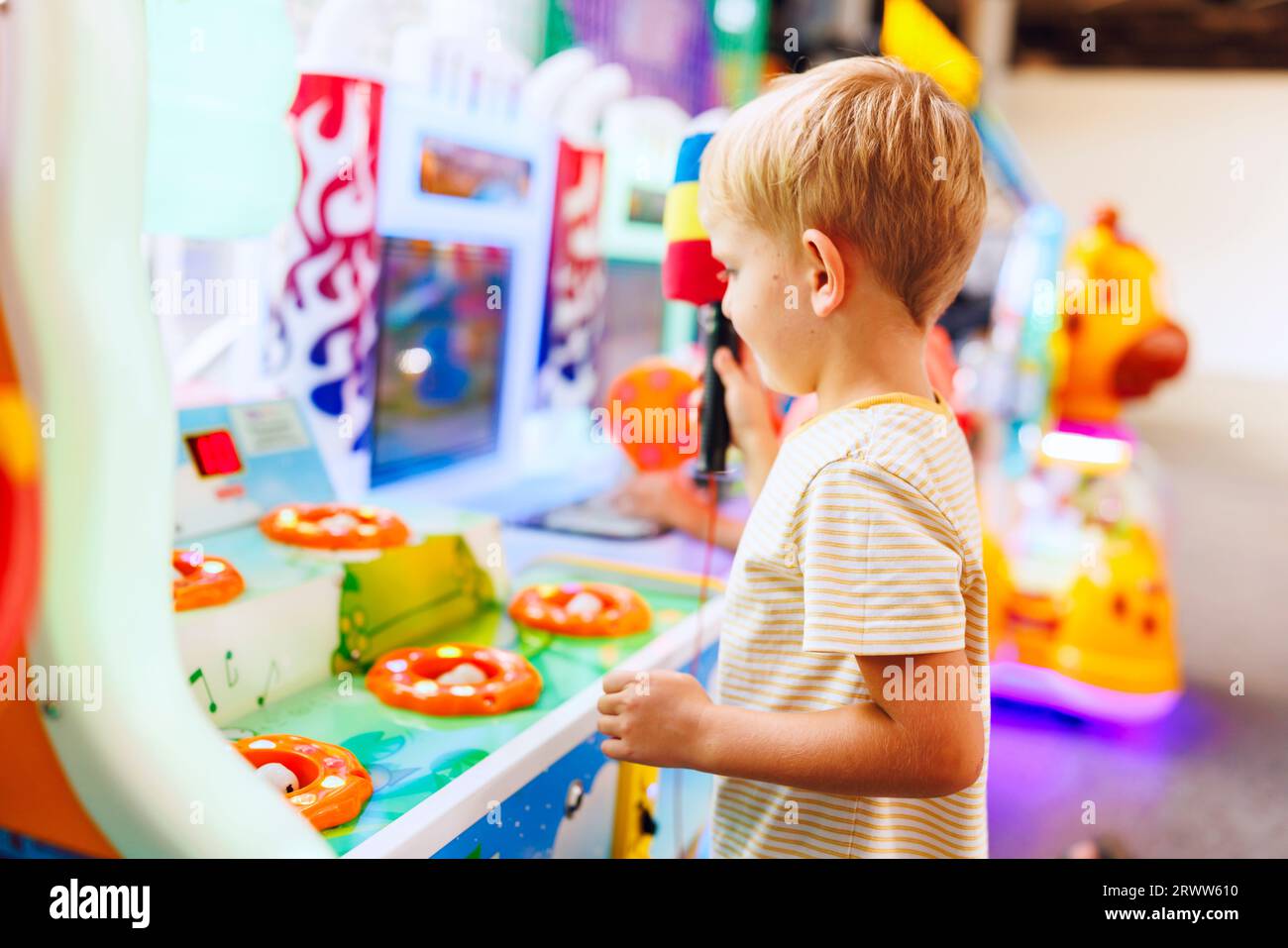 Happy little boy playing fun games on arcade machine at an amusement ...