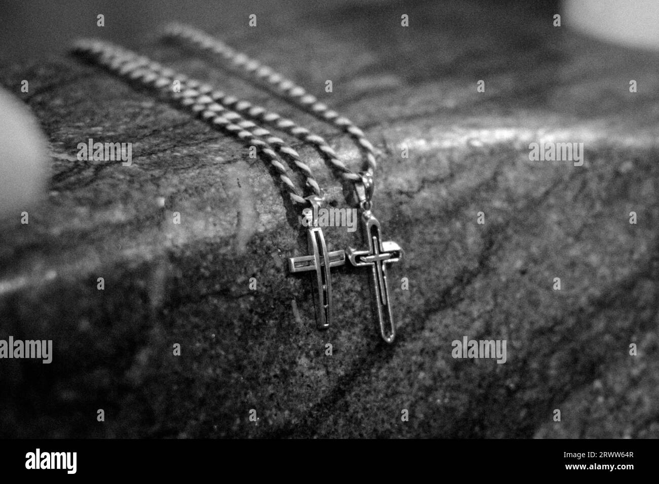 An antique silver crucifix hangs from a chain on top of a rough stone ...