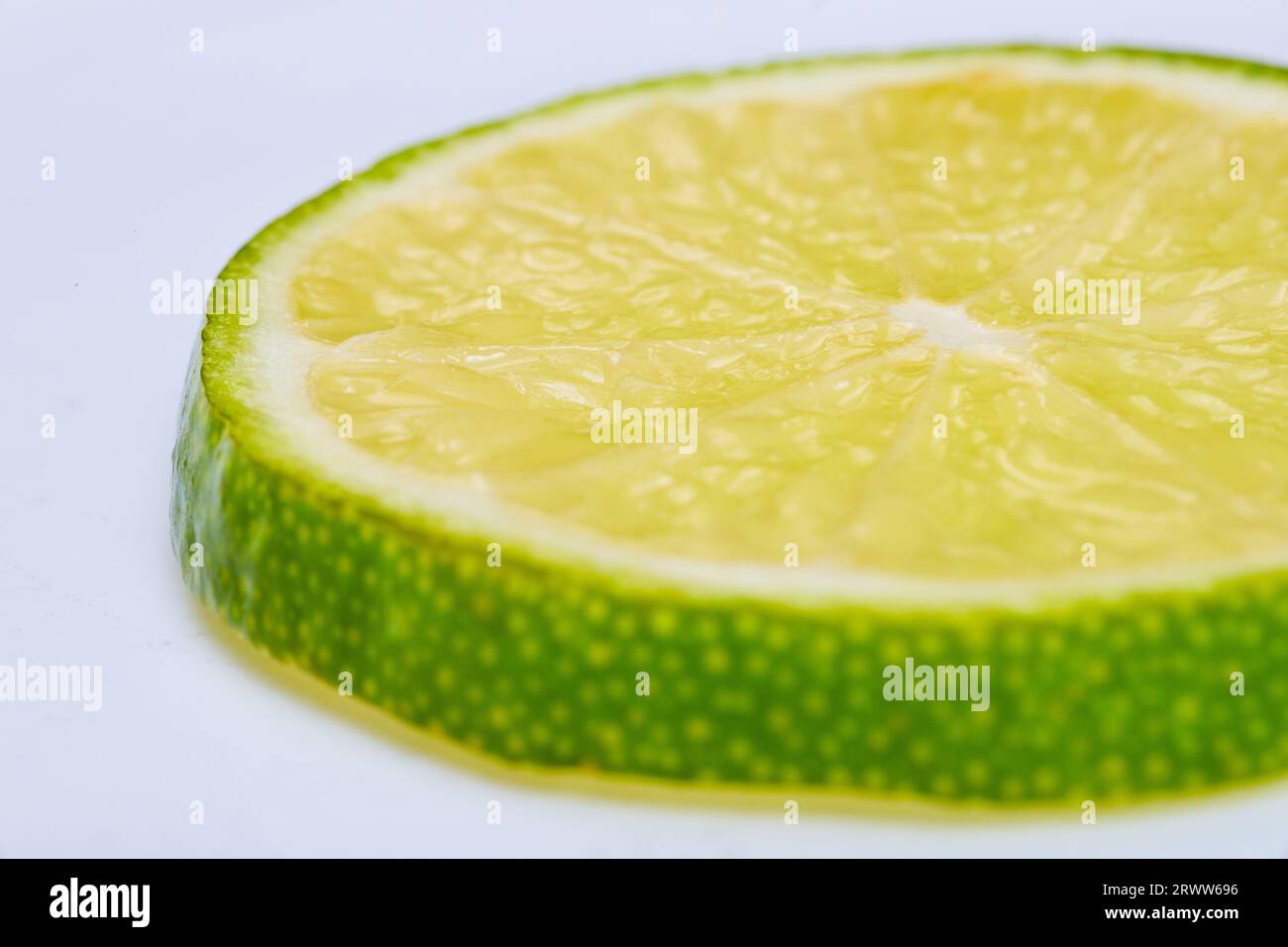Side view of green lime slice against white background Stock Photo - Alamy
