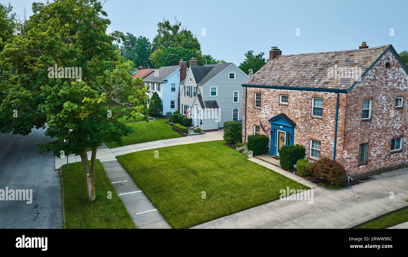 Low aerial of old brick building in neighborhood with neatly trimmed ...