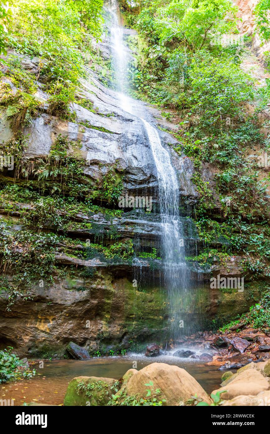 Thin veil of water falling from rocky cliff into a stream in the ...