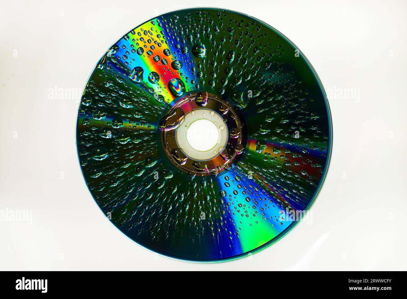 CD with brilliant beams of color and water drops on surface with white ...