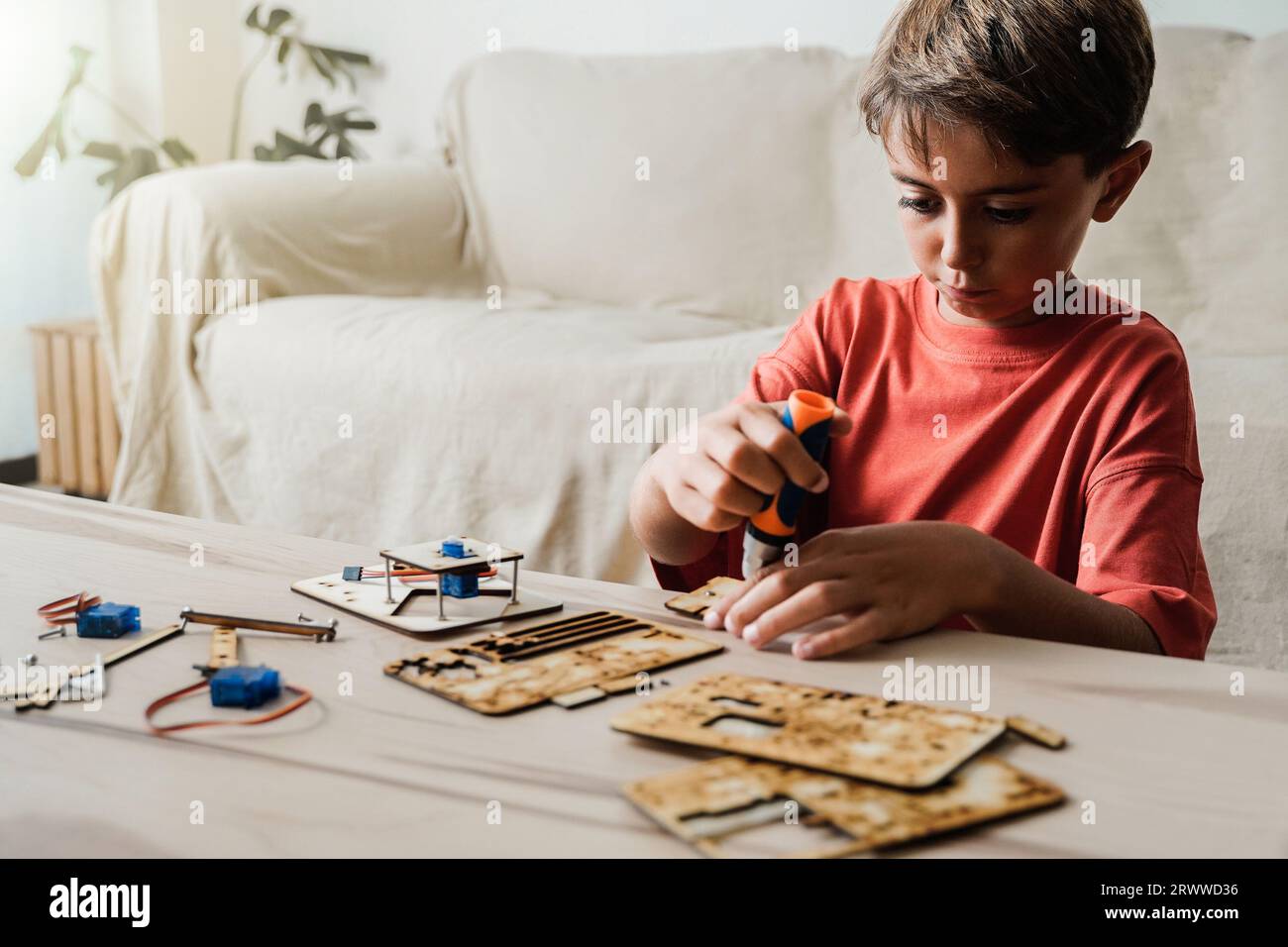 Latino kid building robotic toy machine inside home living room ...