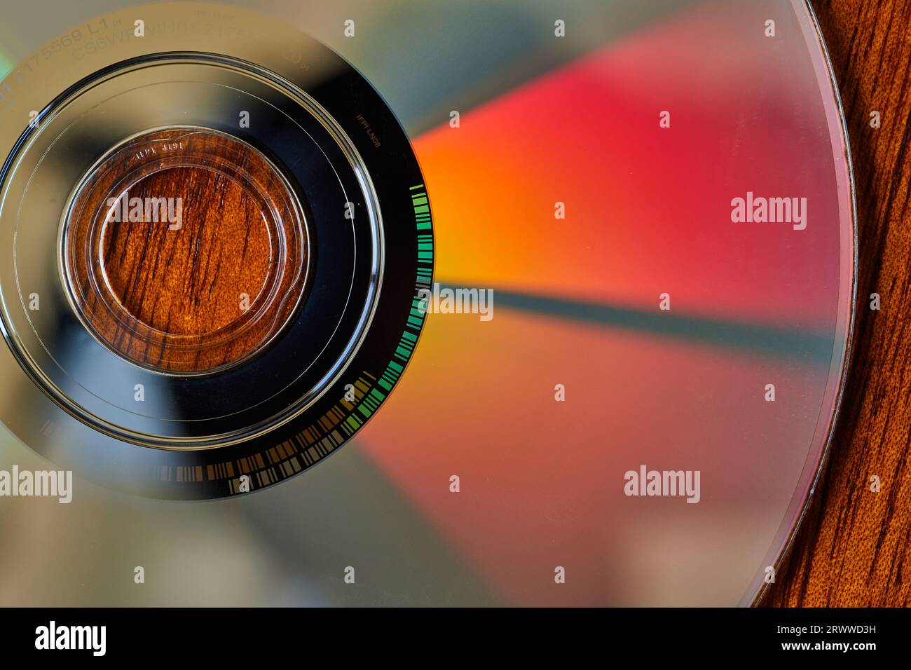 Orange and red light fanning out from black center of CD close up view ...