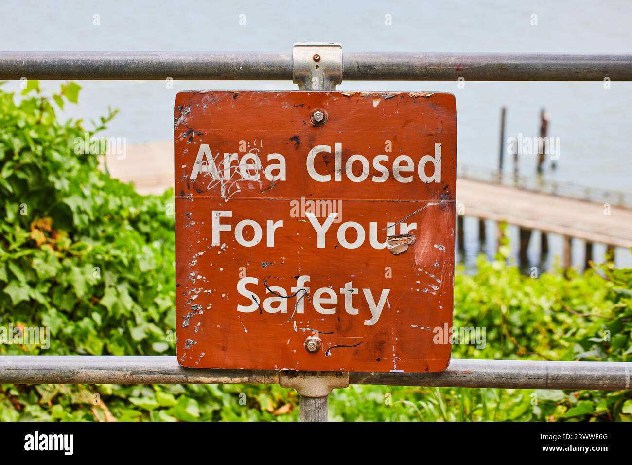 Orange Area Closed For Your Safety sign on metal railing with blurred ...