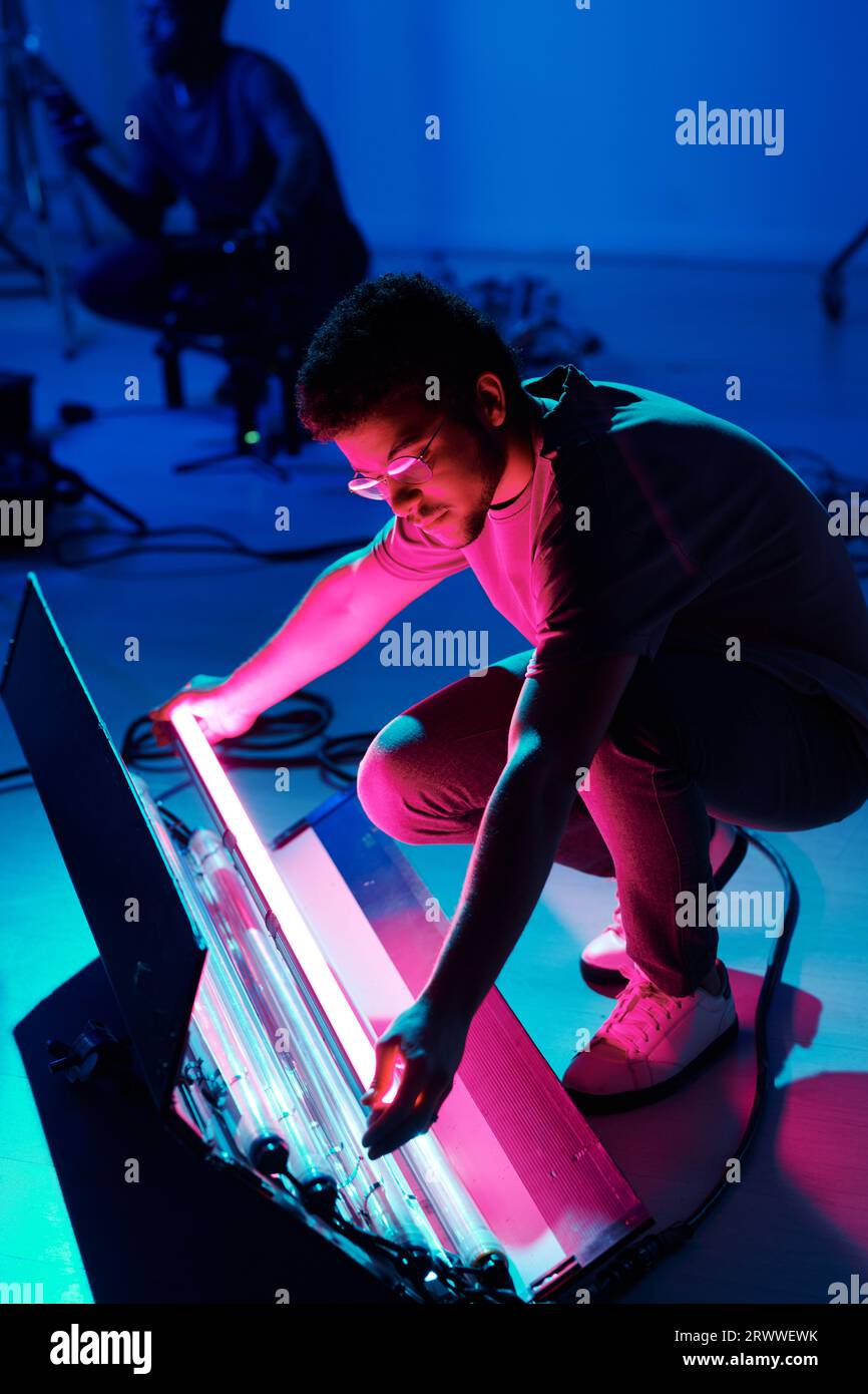 Vertical image of young operator setting the light in studio before ...